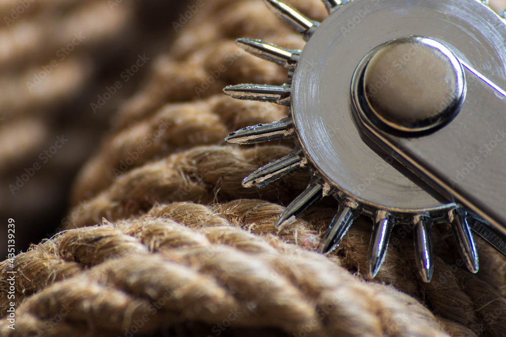 Wartenberg wheel on the background of ropes for shibari, kimbaku. Bdsm ...