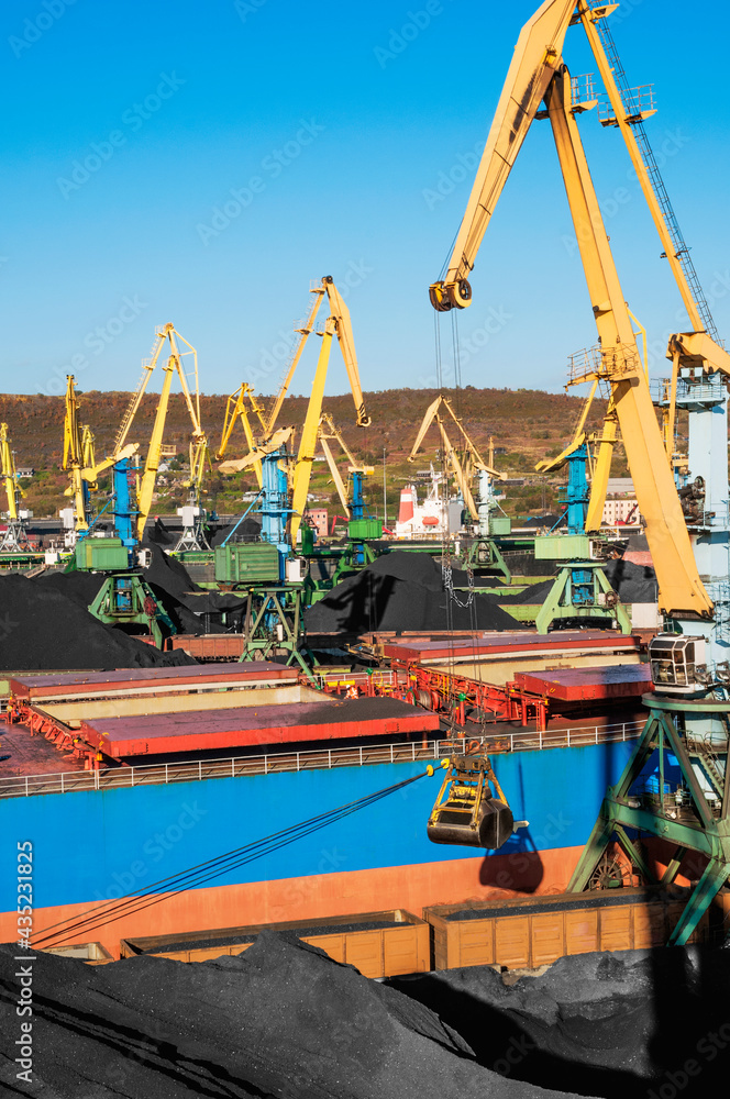 Loading of coal by buckets (grabs) of portal cranes into the holds of a ...