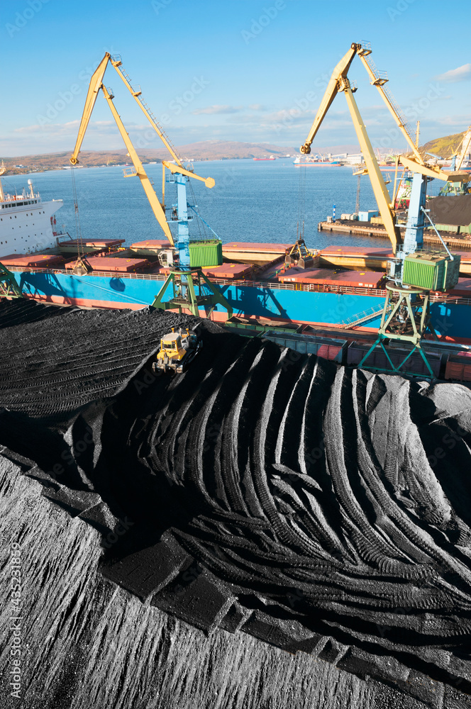 Loading of coal by buckets (grabs) of portal cranes into the holds of a ...
