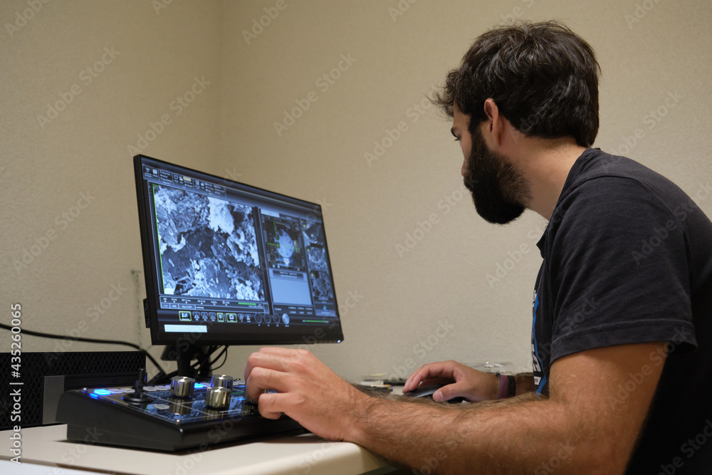 Young man scientist working with scanning electron microscope ...
