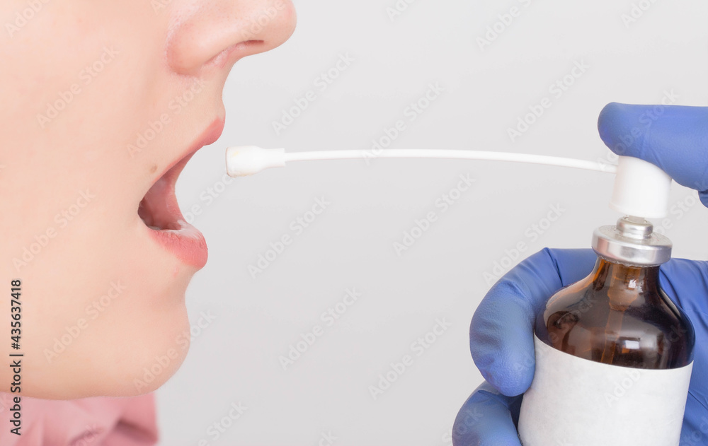 The doctor sprays a local anesthetic to the female patient for a ...