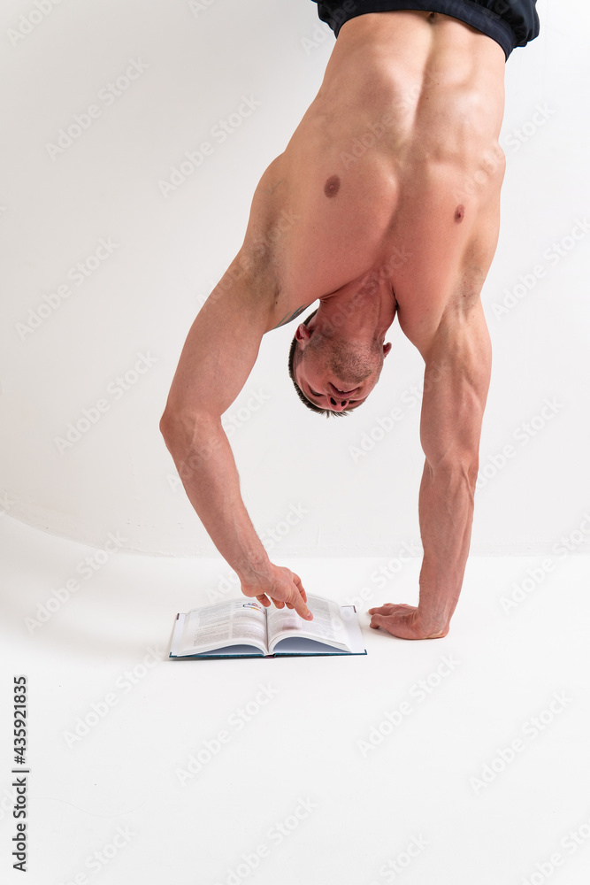 Bodybuilder reads the book on a white background isolated at the bottom ...