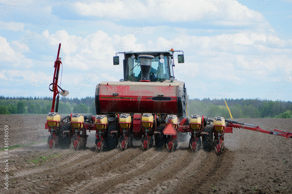 red tractor in a field rear view, tractor planting crops on an ...