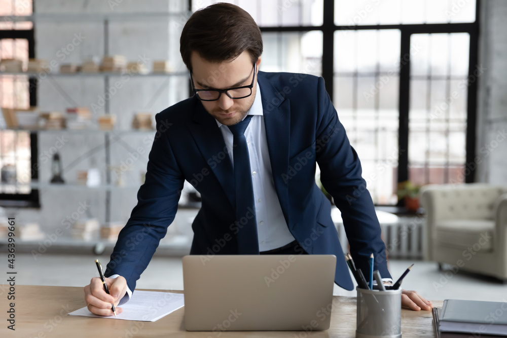 Serious busy business leader signing legal document at workplace in ...