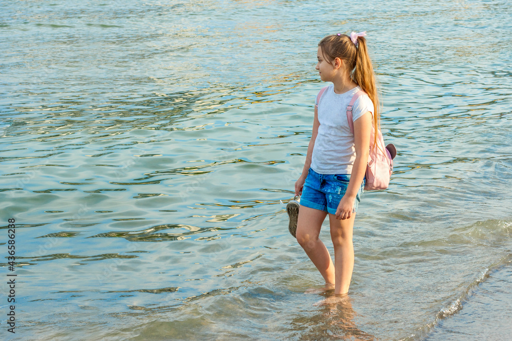 A Cute Teenage Girl In Shorts And A T Shirt Barefoot Walks Along The