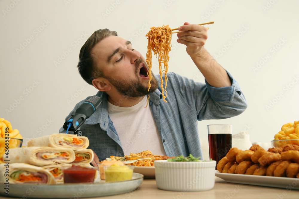 Food blogger eating in front of microphone at table against light ...