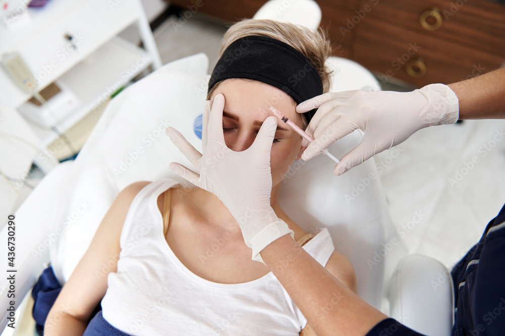 Top view of young woman receiving botulinum toxin injection into face ...