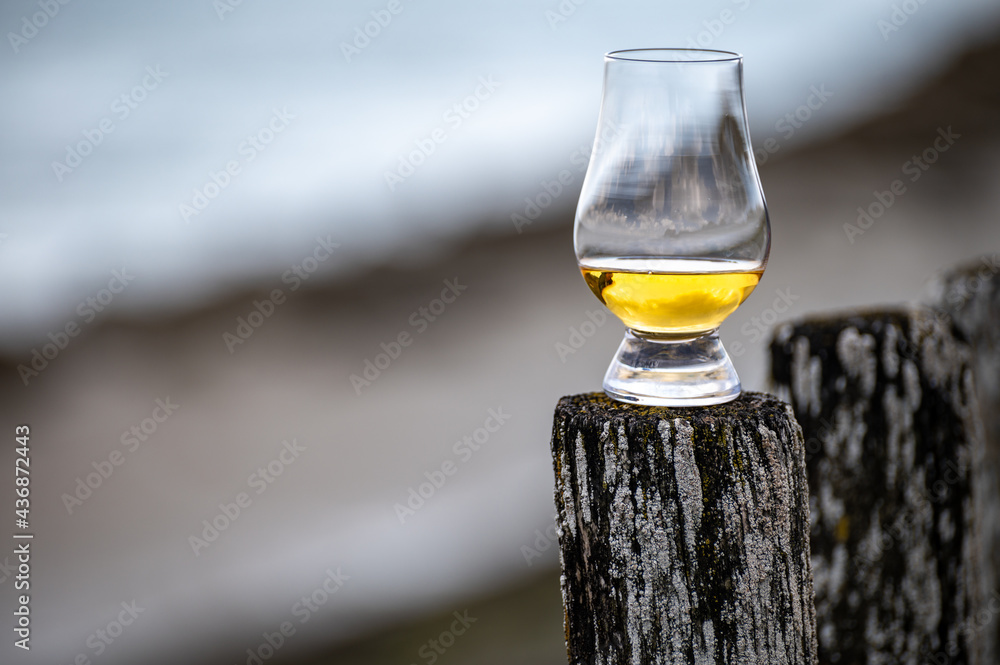 Tasting of dram single malt scotch whisky on seashore in Scotland, old ...