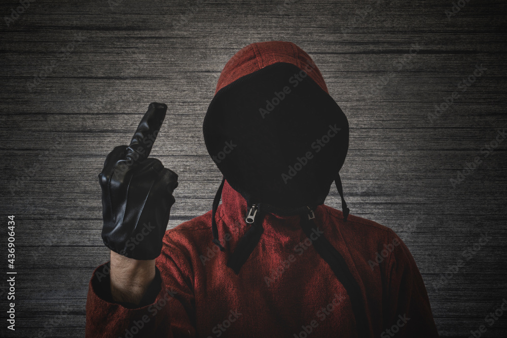 an unrecognizable man without a face in a hood shows the middle finger ...