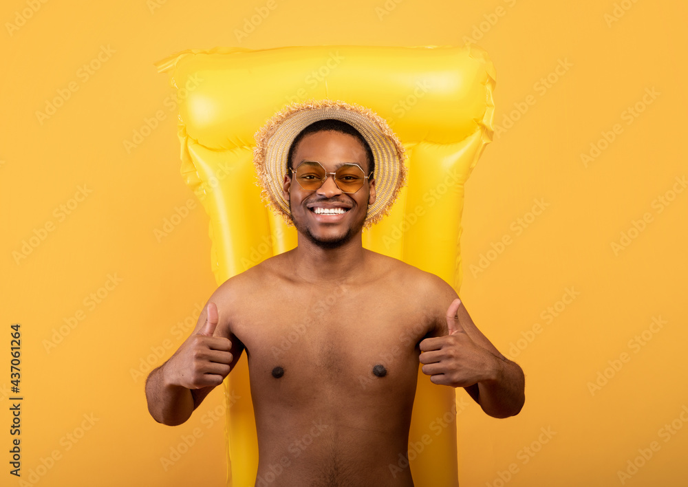 Top view of happy black man lying on inflatable lilo and showing thumbs ...