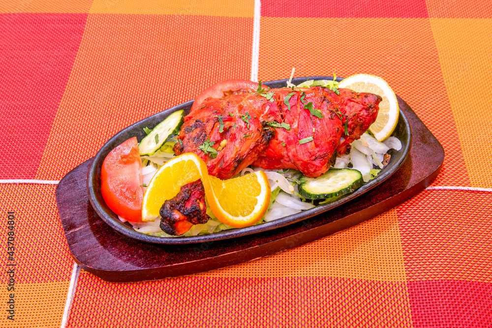 Grilled chicken thigh in Hindu tandoori style with bright red color and ...