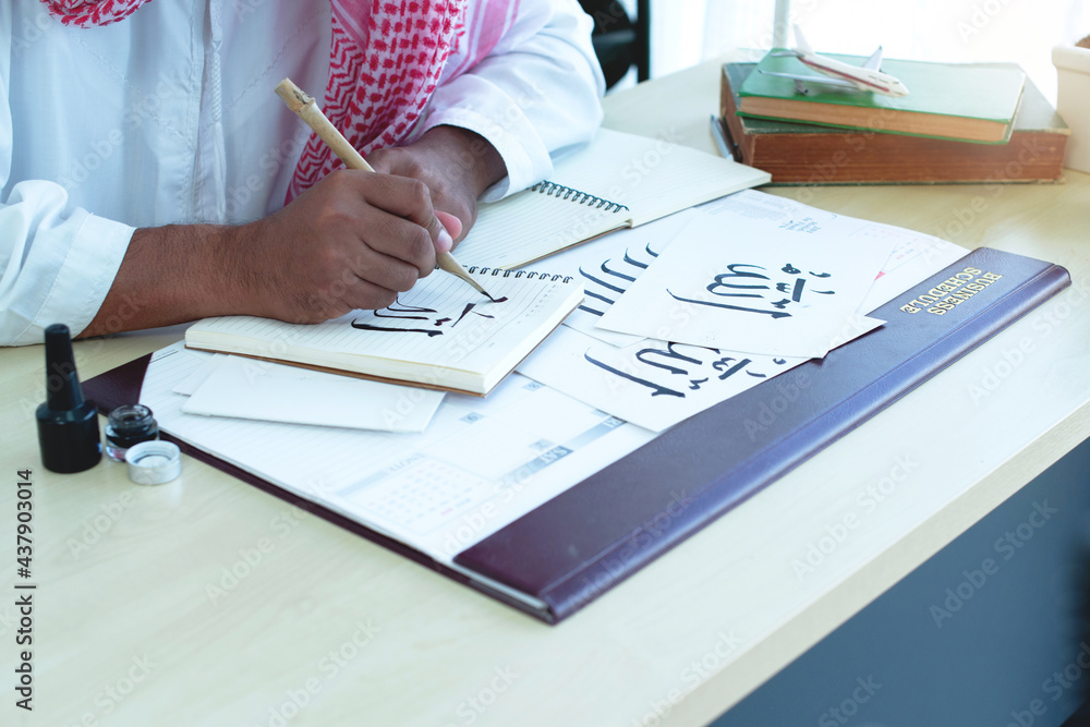 Arab men practicing writing Arabic ้with bamboo pens and ink on paper ...