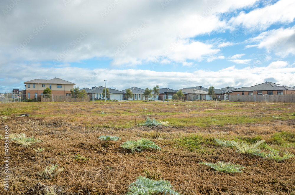 Fenced vacant land near some Australian new residential suburban houses ...