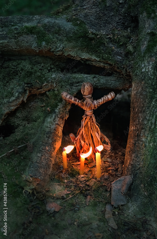 magic witchcraft doll made of tree bast and burning candles in dark ...