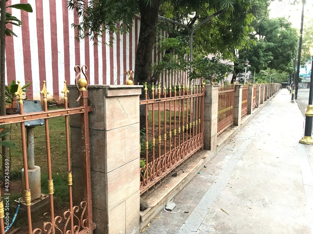 Temple compound wall with brick pillars and straight rods in between in ...