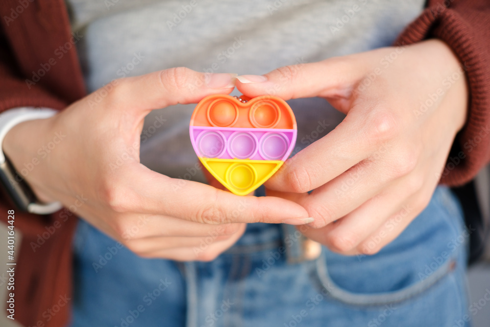 Girl holding rainbow bubble pop it fidget toy. For autistic patients to relieve stress and help ...