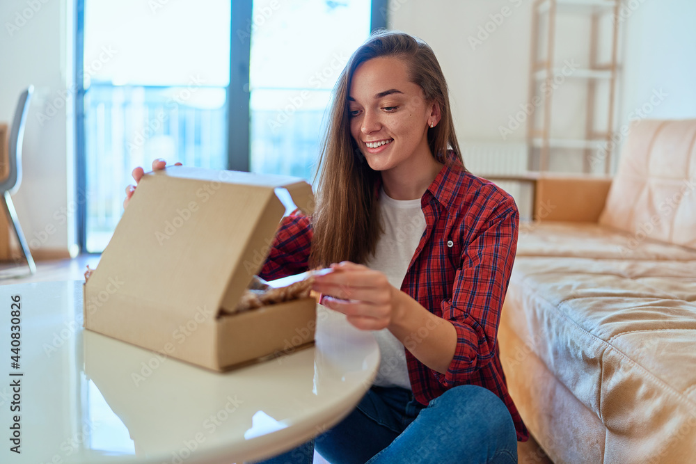 Young happy joyful smiling girl customer received parcel and unpacking ...