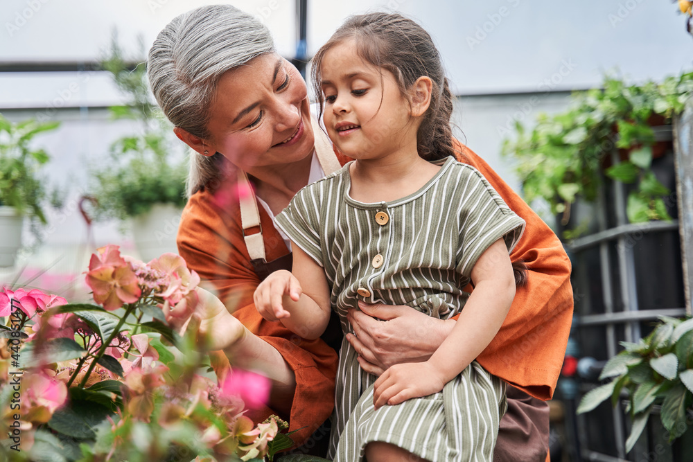 Granddaughter embracing with her grandmother while helping to digging a ...