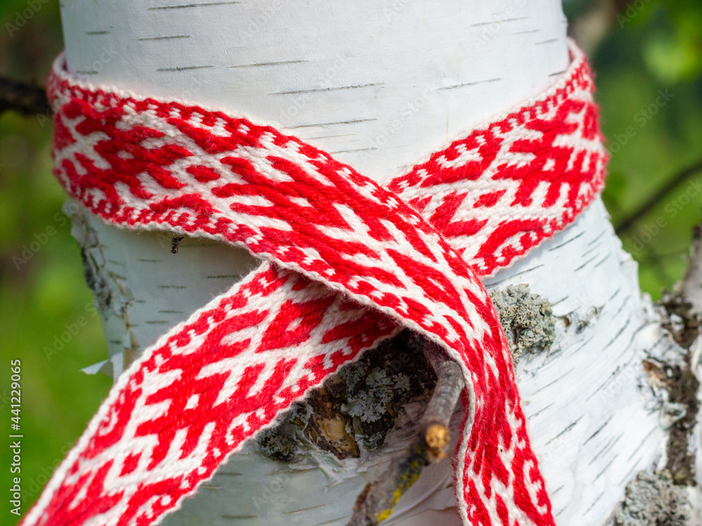 Red and white ribbon with ornament of traditional Slavic signs tied on ...