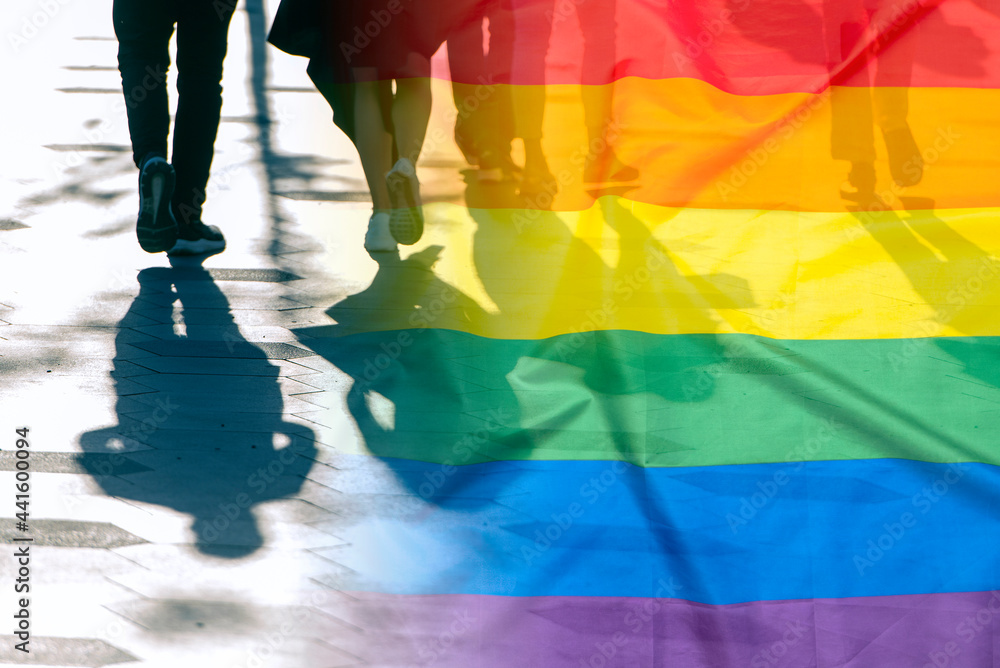 Rainbow LGBT flag, shadows and silhouettes of people on a road ...