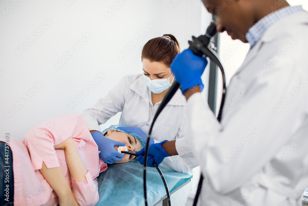 Female young patient lying on the couch in clinic, while male African ...