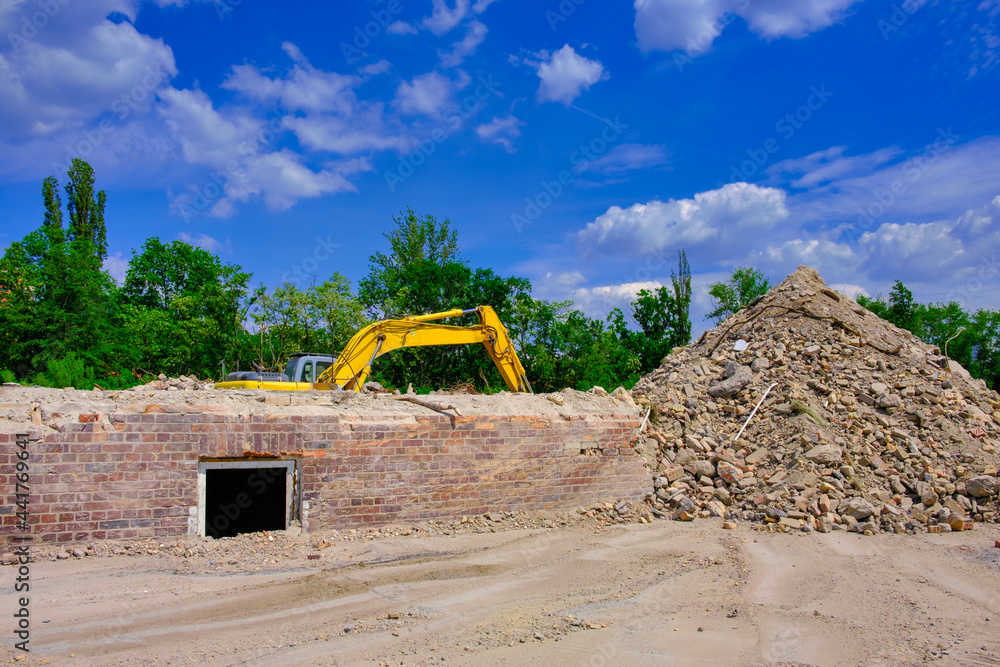 yellow excavator doing demolition work on a construction site. Also ...