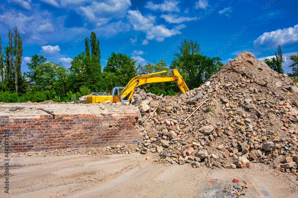 yellow excavator doing demolition work on a construction site. Also ...