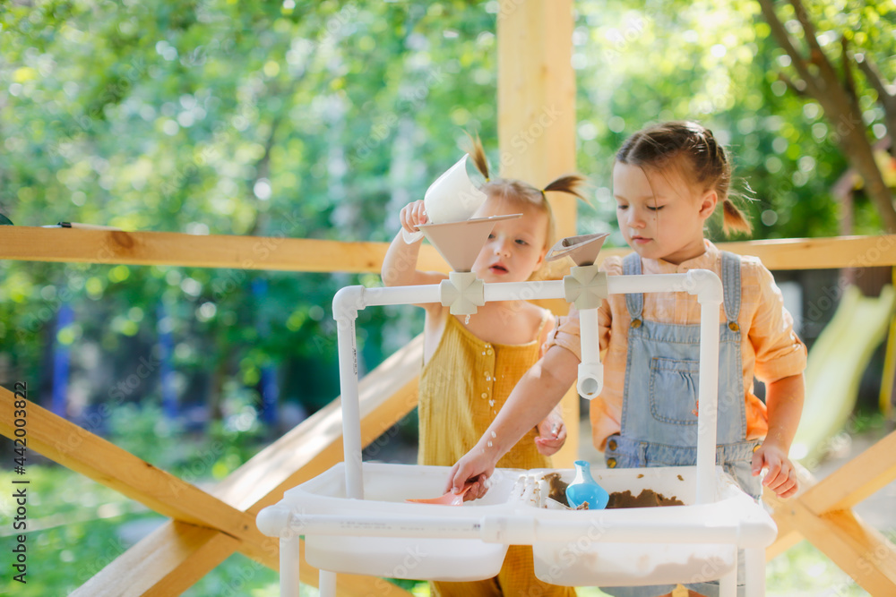 Happy sister kids play with sand and water in sensory baskets on the ...