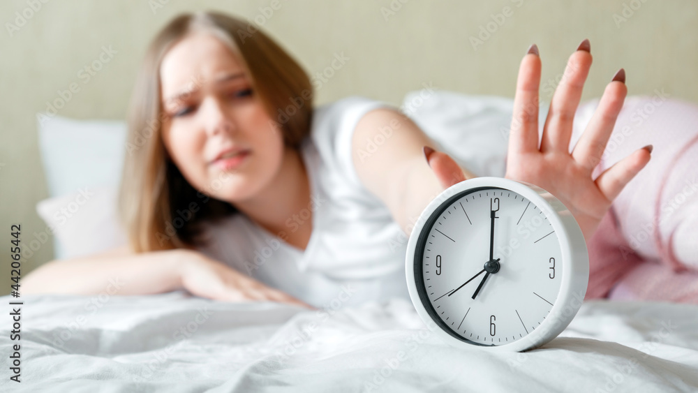 Overslept young woman awake in pajamas turns off alarm clock in hurry ...