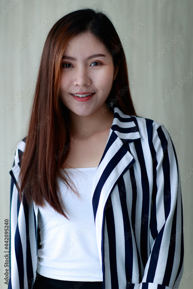 attractive indoor portrait of beautiful young woman on black & white stripe suit standing with ...