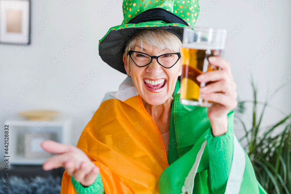 Old Irish lady wearing Irish symbols drinking beer, toasting towards ...