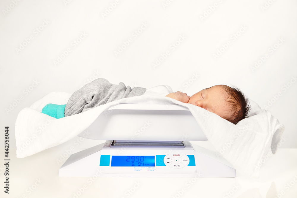 Newborn baby boy laying on baby scale for weight checking Stock Photo ...