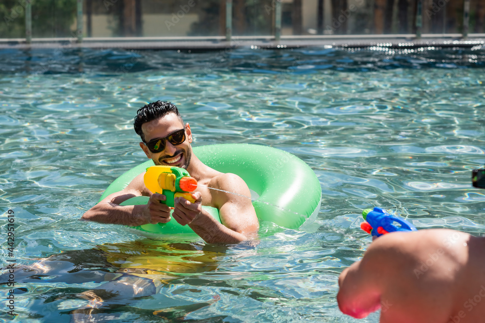 excited muslim man enjoying water pistols battle with friend in ...