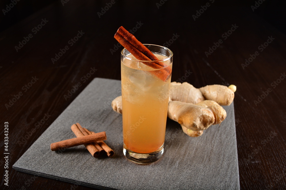 iced ginger soda mocktail with cinnamon kombucha in glass on bar counter dark night background ...