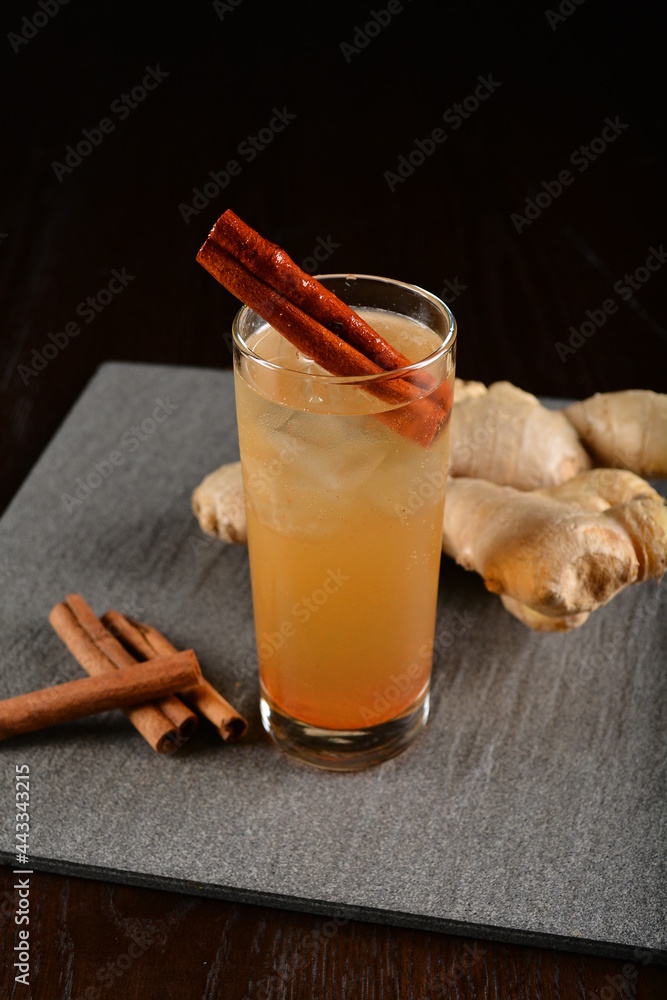 iced ginger soda mocktail with cinnamon kombucha in glass on bar counter dark night background ...