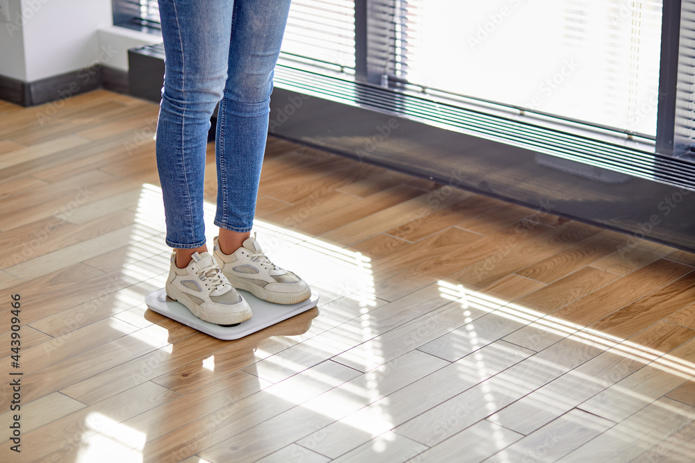 Weight loss. Cropped slim lady standing on weighing scale, checking ...