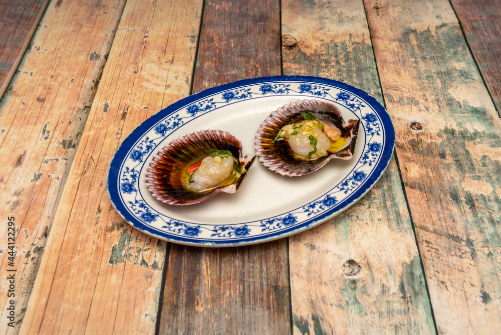 White tray with blue border with two scallops with their shells cooked ...