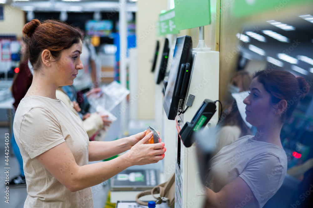 Caucasian woman uses a self-checkout counter. Self-purchase of ...