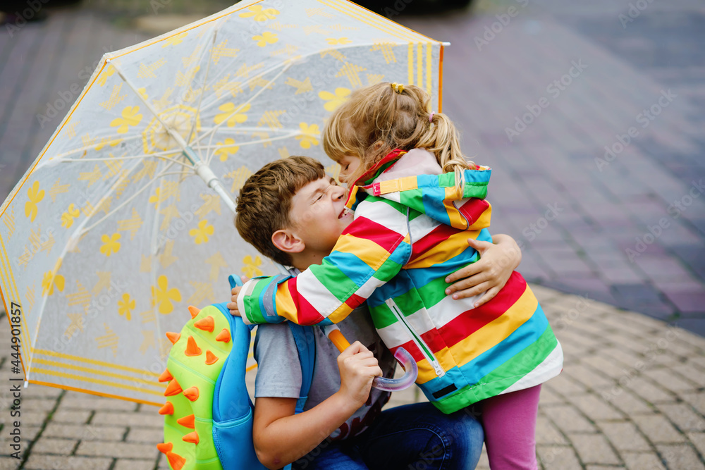 School kid boy picks up the little sister, preschool girl from ...