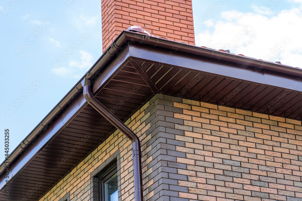 close-up view of house with brown roof and filing of roof overhangs ...