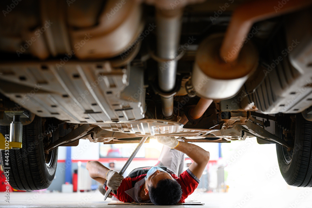 ภาพถ่าย Stock Asian auto mechanic sleeps under the car to Check the car ...