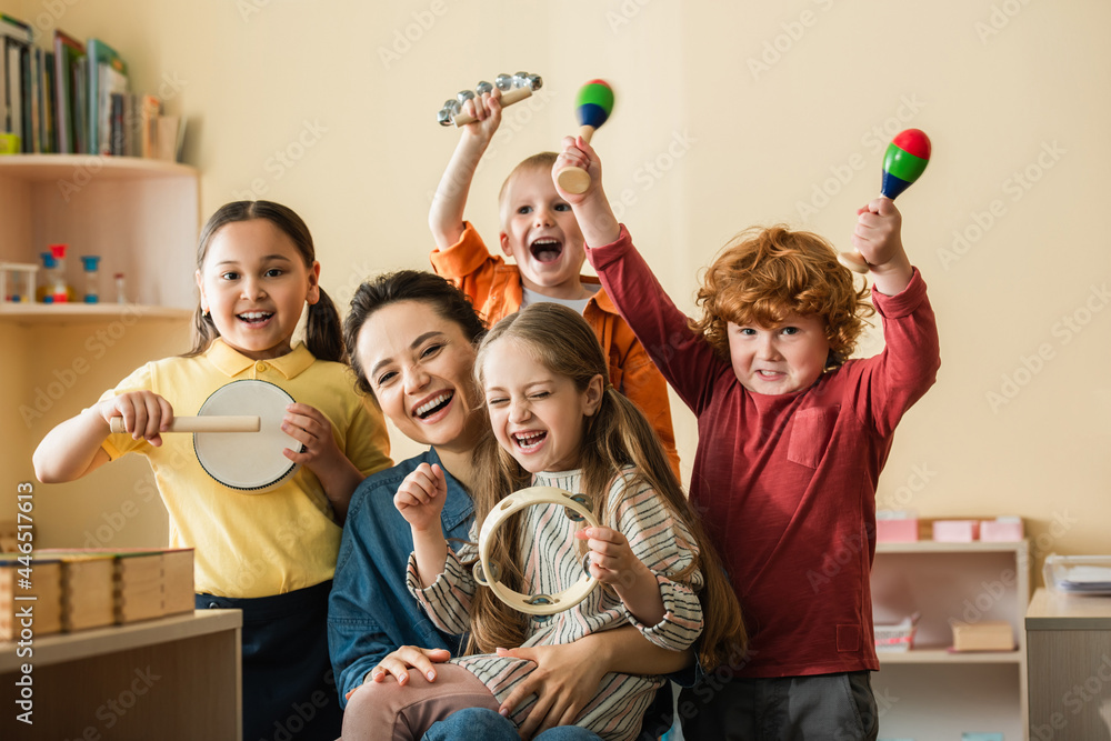 excited multiethnic kids playing musical instruments near happy teacher ...
