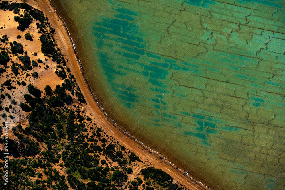 Abstract aerial view of blue-green water in shifting red deposition of ...
