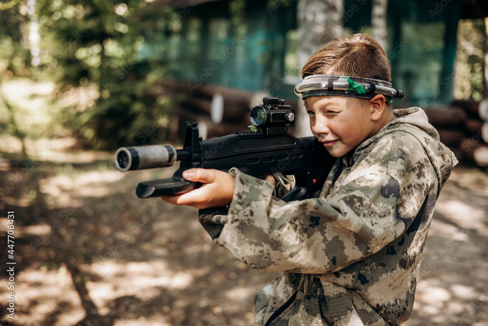 Boy looking into the optical sight a weapon. Children playing laser tag shooting game in outdoor ...