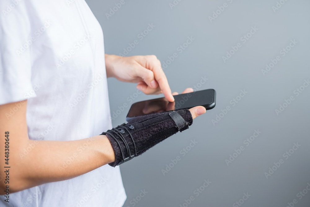 woman holding her wrist pain because using smartphone long time. De ...