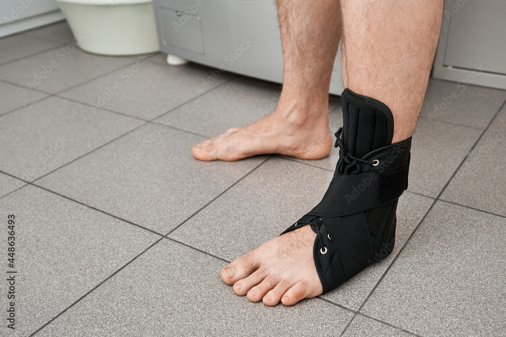The male leg is fixed in a medical bandage. Ankle fracture or sprain ...
