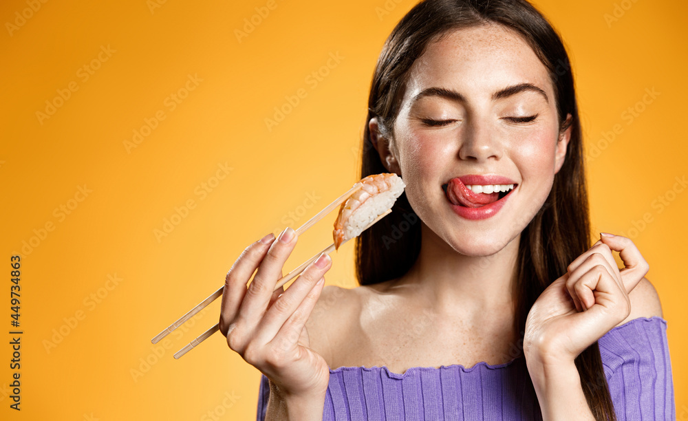 Sexy woman eating sashimi sushi with chopsticks, licking lips from ...
