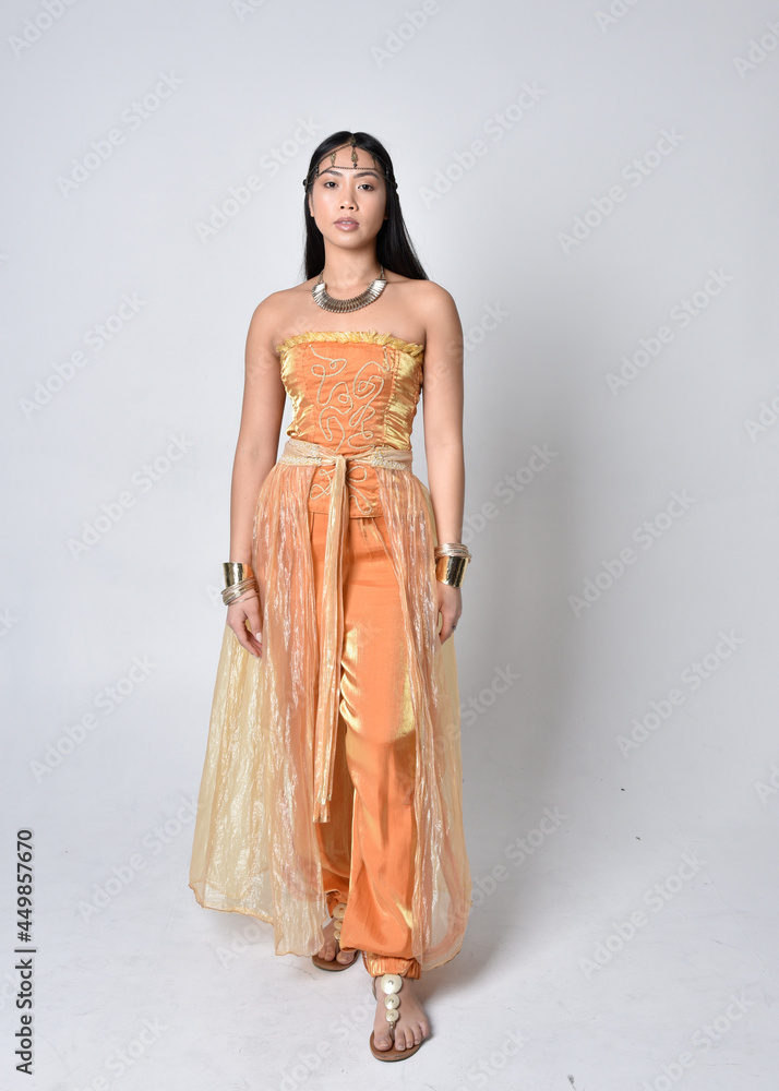 Full length portrait of pretty young asian woman wearing golden Arabian ...