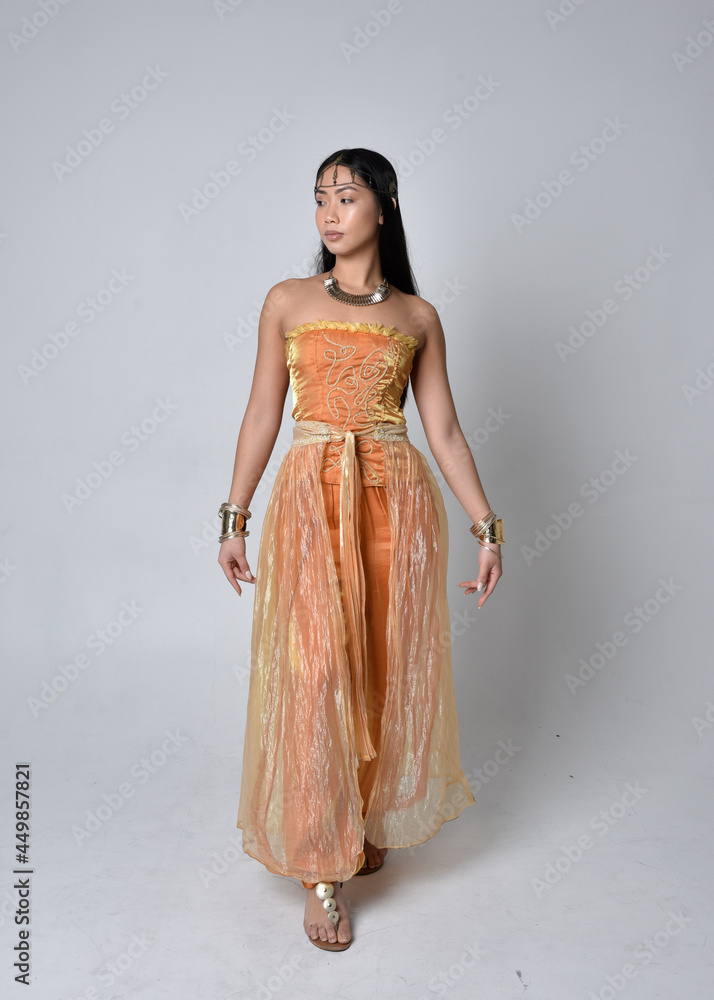 Full length portrait of pretty young asian woman wearing golden Arabian ...