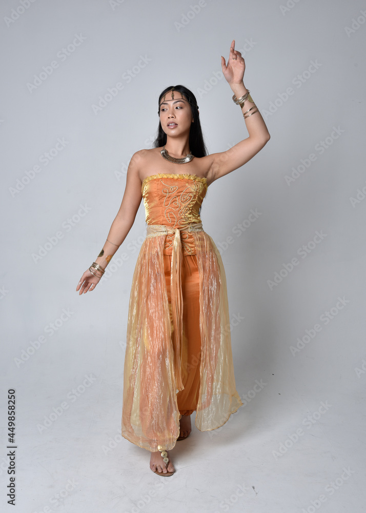 Full length portrait of pretty young asian woman wearing golden Arabian ...